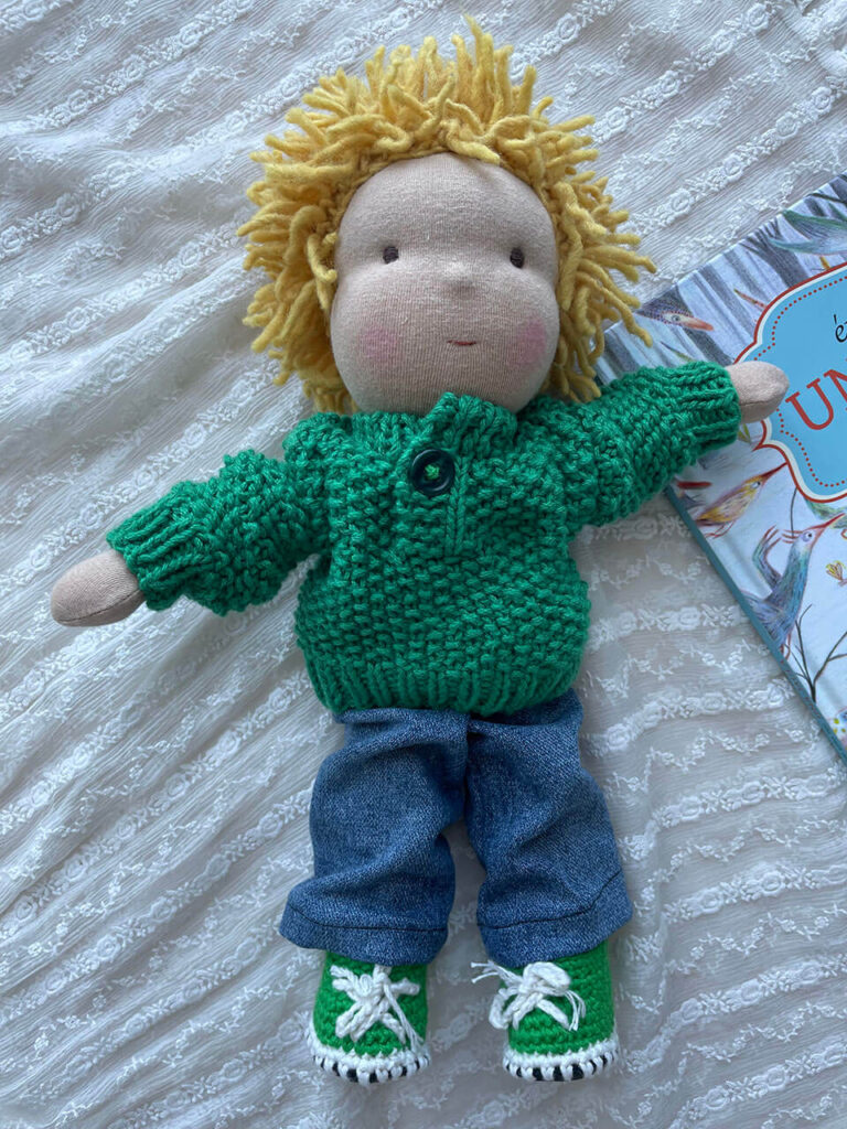Muñeco pequeño con pelo amarillo, suéter verde hoja y pantalones de ...