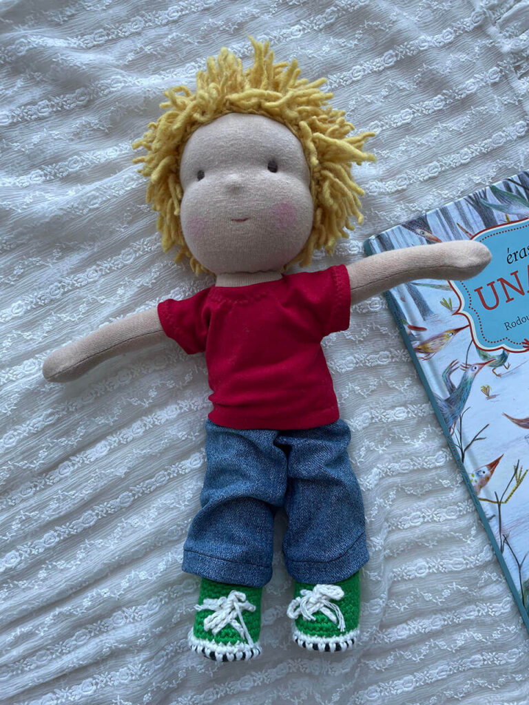Muñeco pequeño con pelo amarillo, suéter verde hoja y pantalones de ...